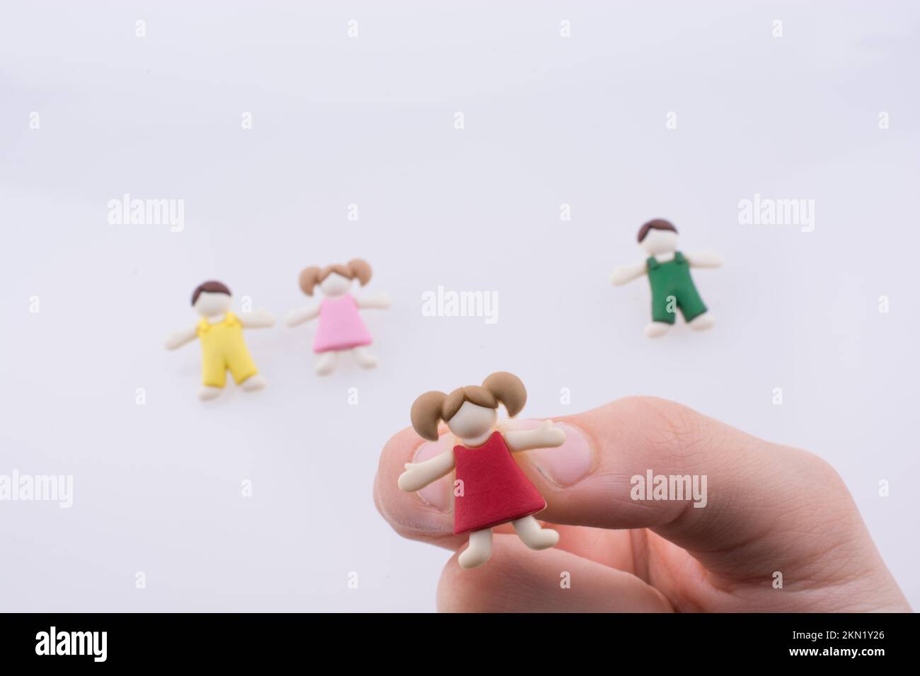 Hand holding colorful dressed children figure on a white background ...