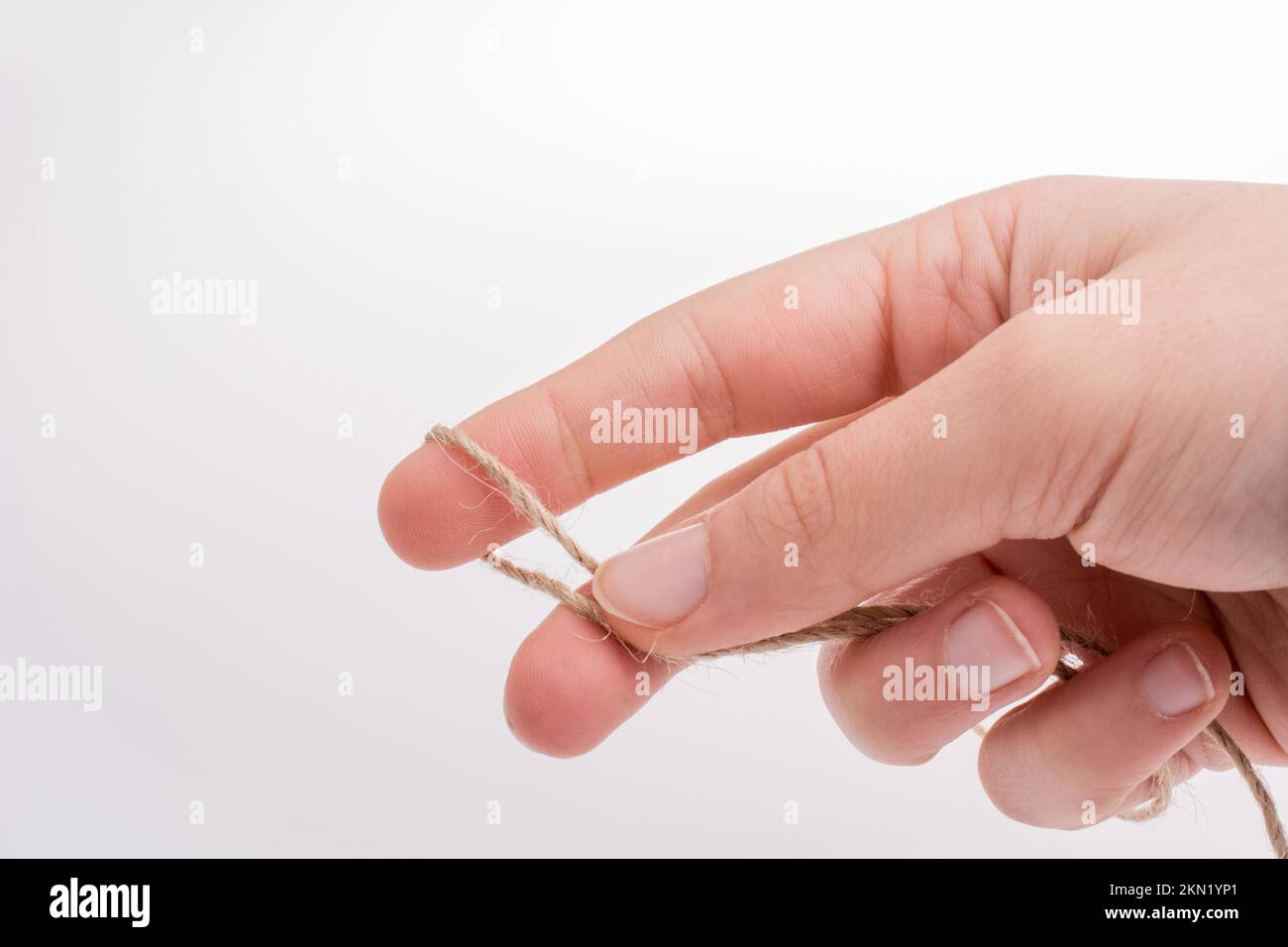 Hand holding linen thread on a white background Stock Photo - Alamy