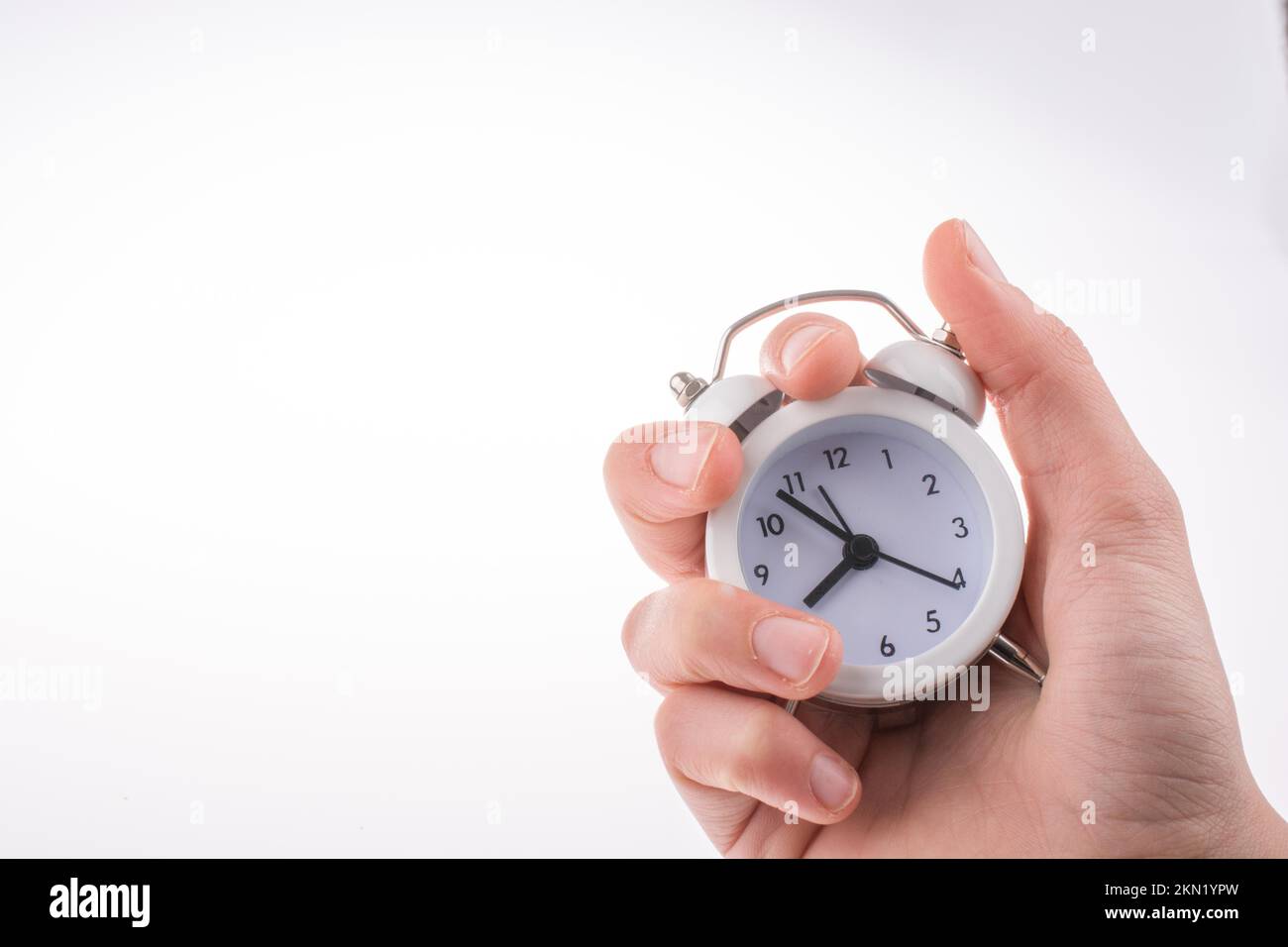 Alarm clock in hand on a white background Stock Photo - Alamy