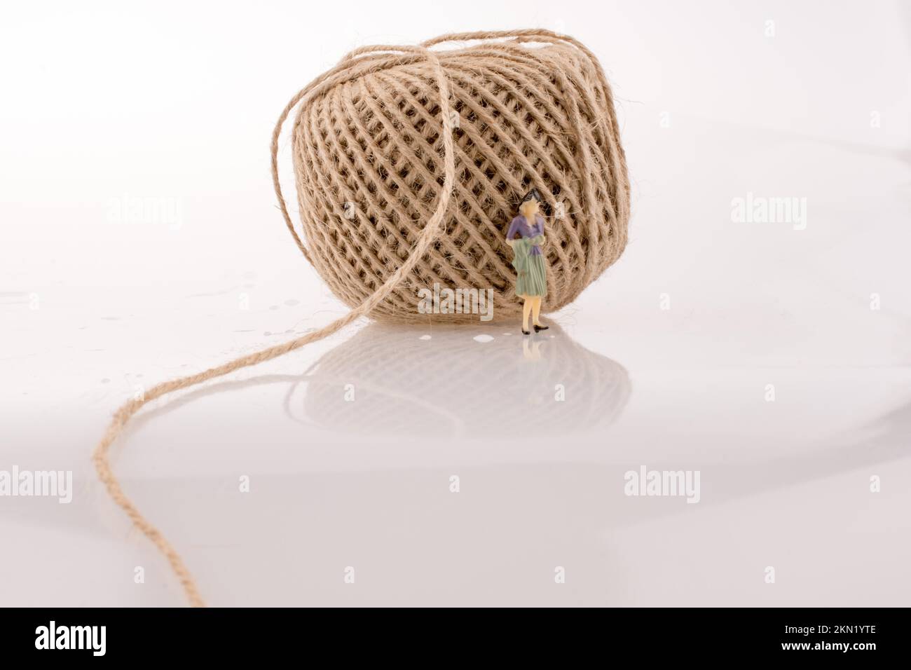 Woman figure beside a linen spool of thread on a white background Stock ...