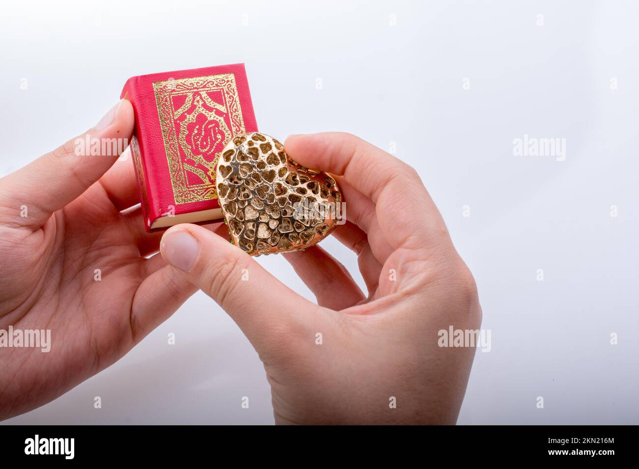 Hand holding Heart shape and Islamic Holy Book Quran Stock Photo - Alamy