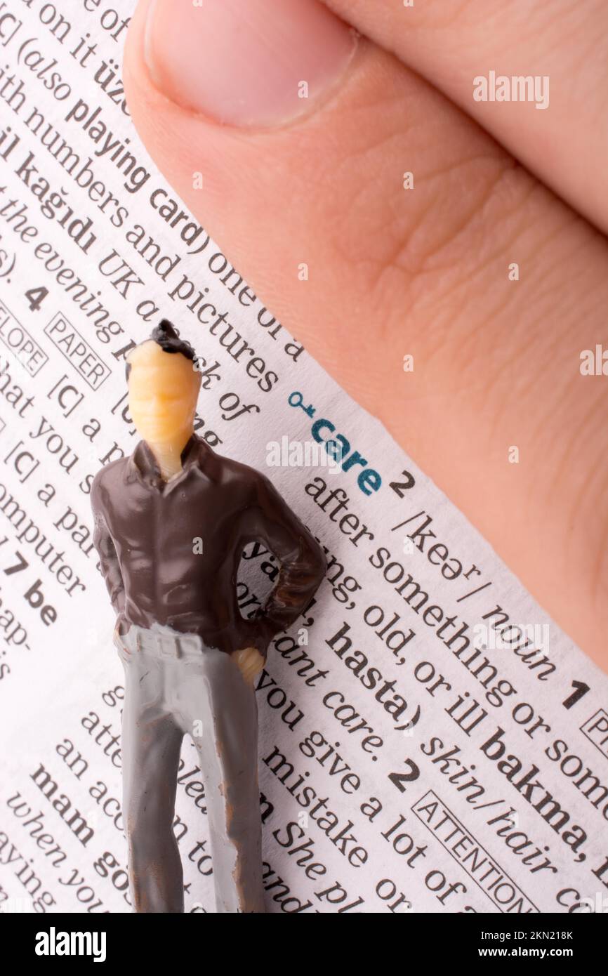Hand holding a human figure on a newspaper by the word care Stock Photo ...