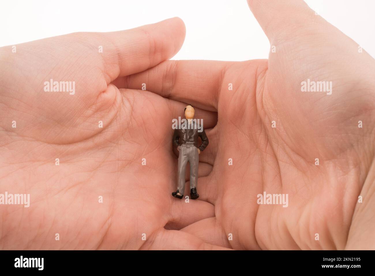 Hand holding human figure on a white background Stock Photo - Alamy