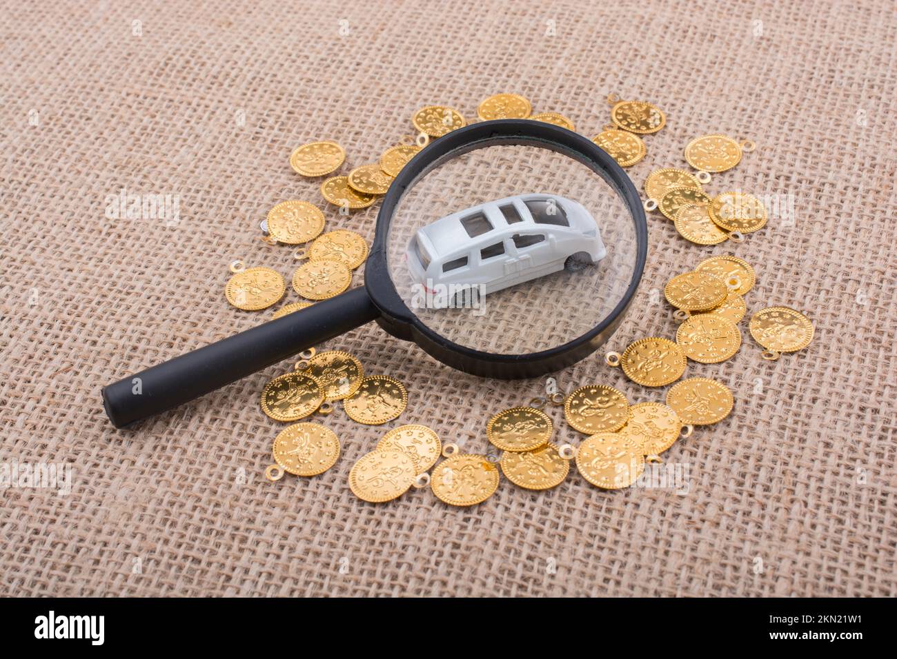Fake gold coins and toy car under magnifying glass Stock Photo - Alamy