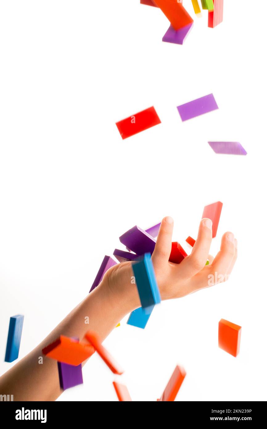 Falling colorful domino onto a hand Stock Photo - Alamy