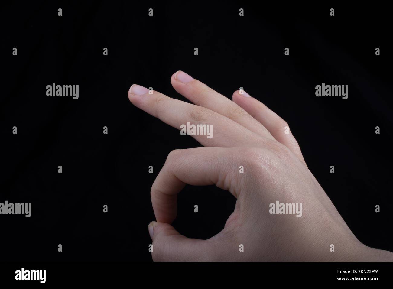 Hand gesturing sign ok okay agree on black background Stock Photo - Alamy