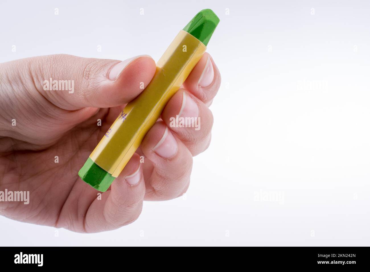 Hand holding a green crayon on a white background Stock Photo - Alamy