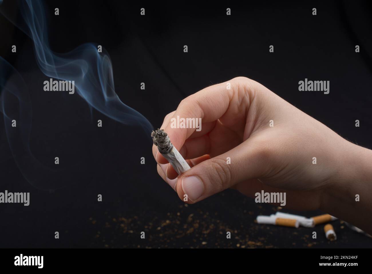 Hand is holding smoking cigarette with smoke around Stock Photo - Alamy