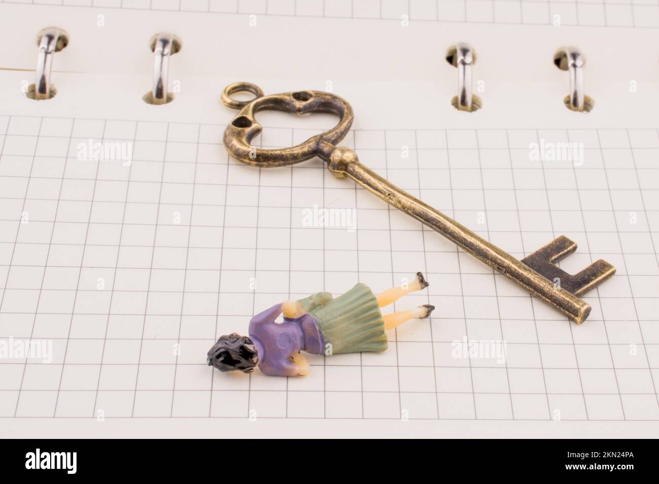 Human figure near a key on a white spiral notebook Stock Photo - Alamy