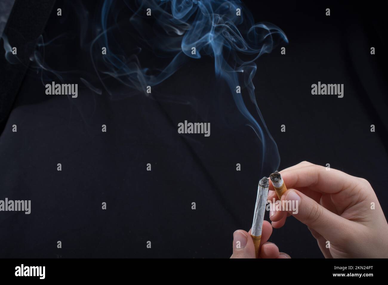 Hand is holding smoking cigarette with smoke around Stock Photo - Alamy