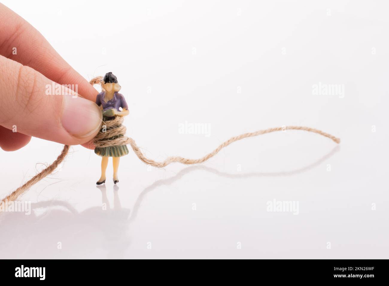Woman figure in hand tied with a linen thread on a white background ...