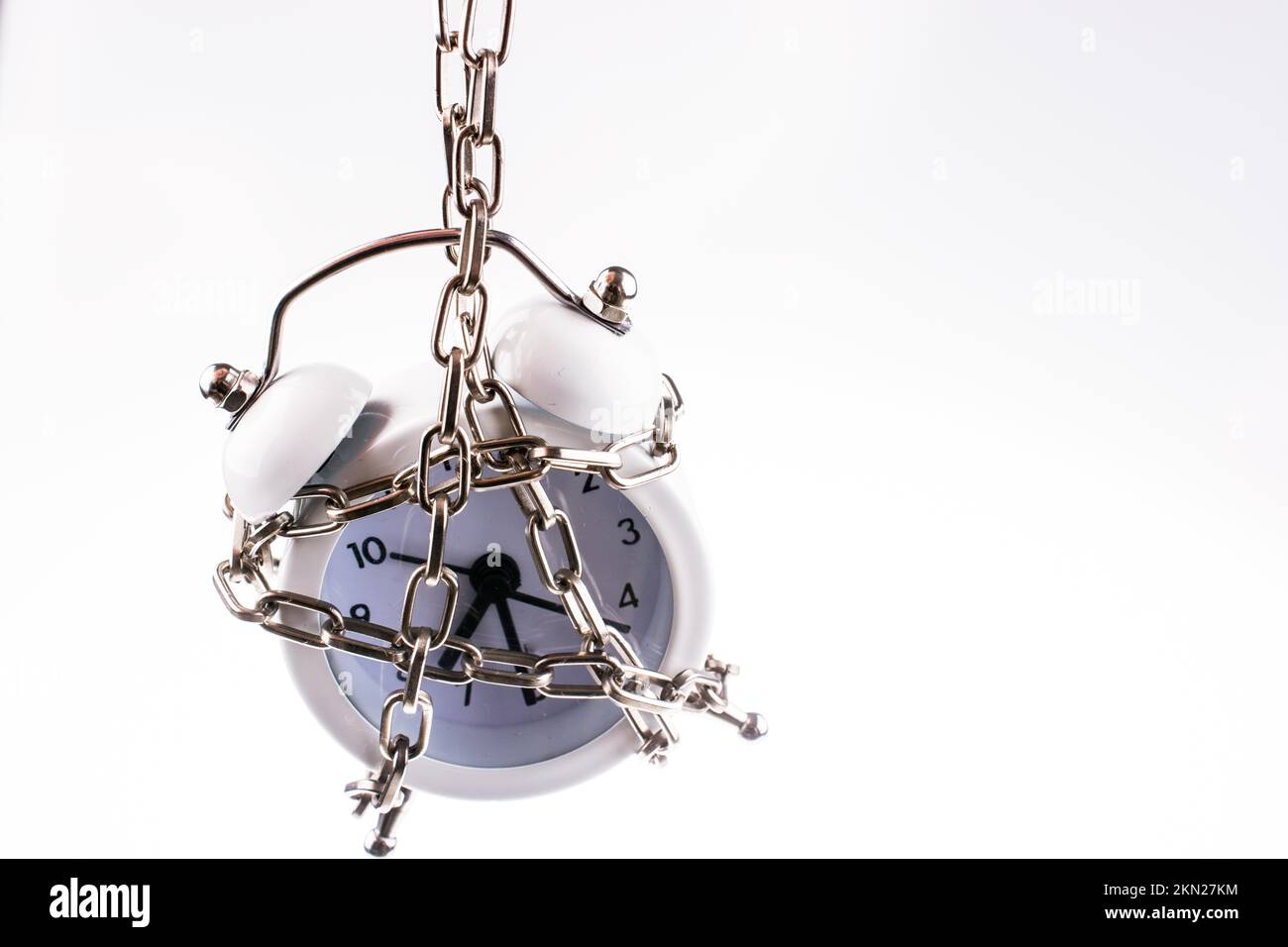 White color alarm clock in chain on a white background Stock Photo - Alamy
