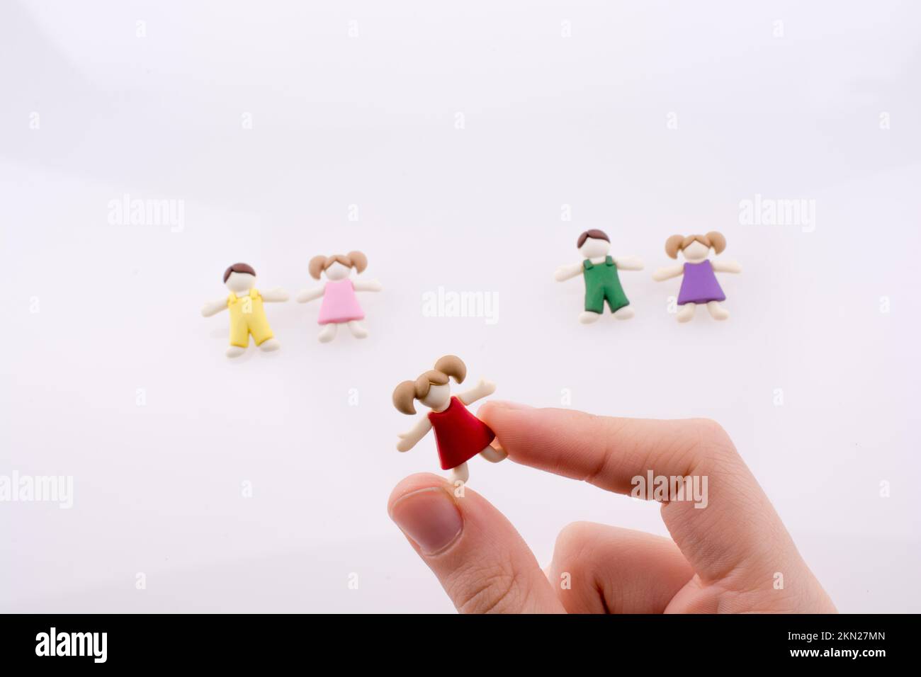 Hand holding colorful dressed children figure on a white background ...