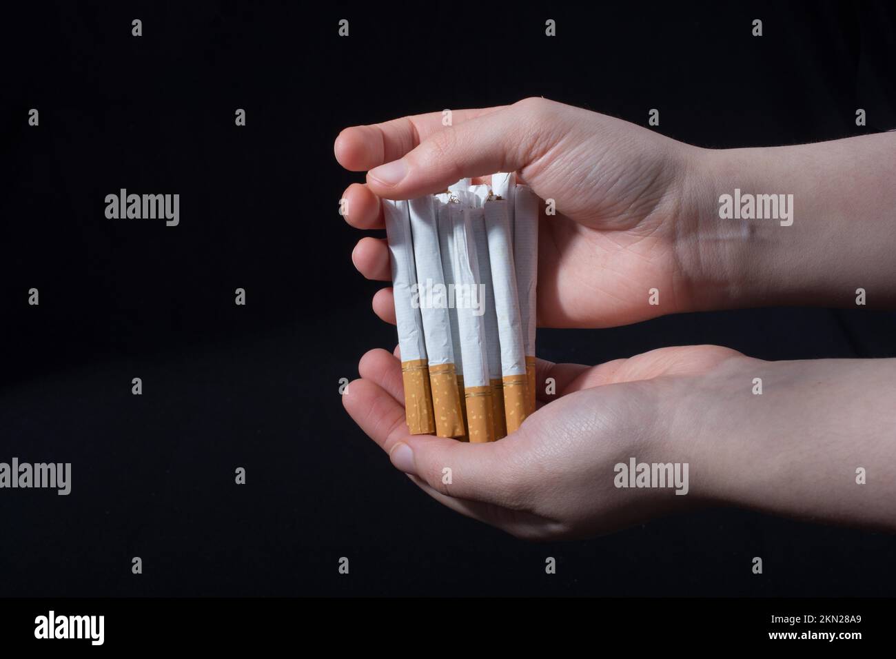 Hand is giving out bundle of cigarettes on black background Stock Photo ...