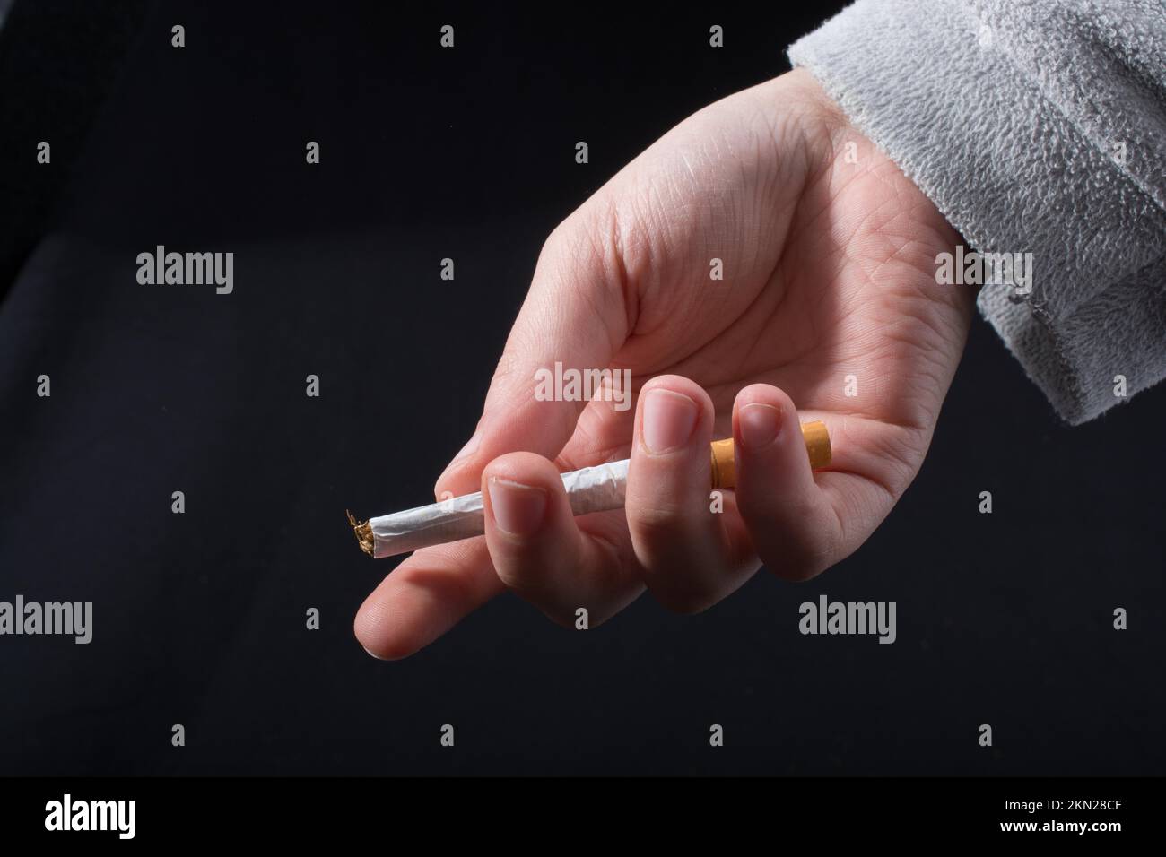 Hand is giving out cigarette on a black background Stock Photo - Alamy