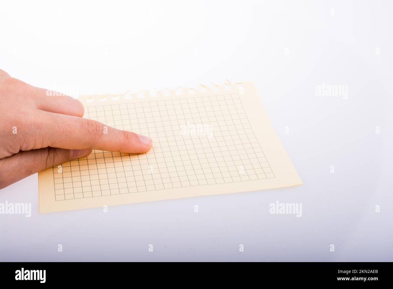 Hand on a sheet of checked paper on a white background Stock Photo - Alamy