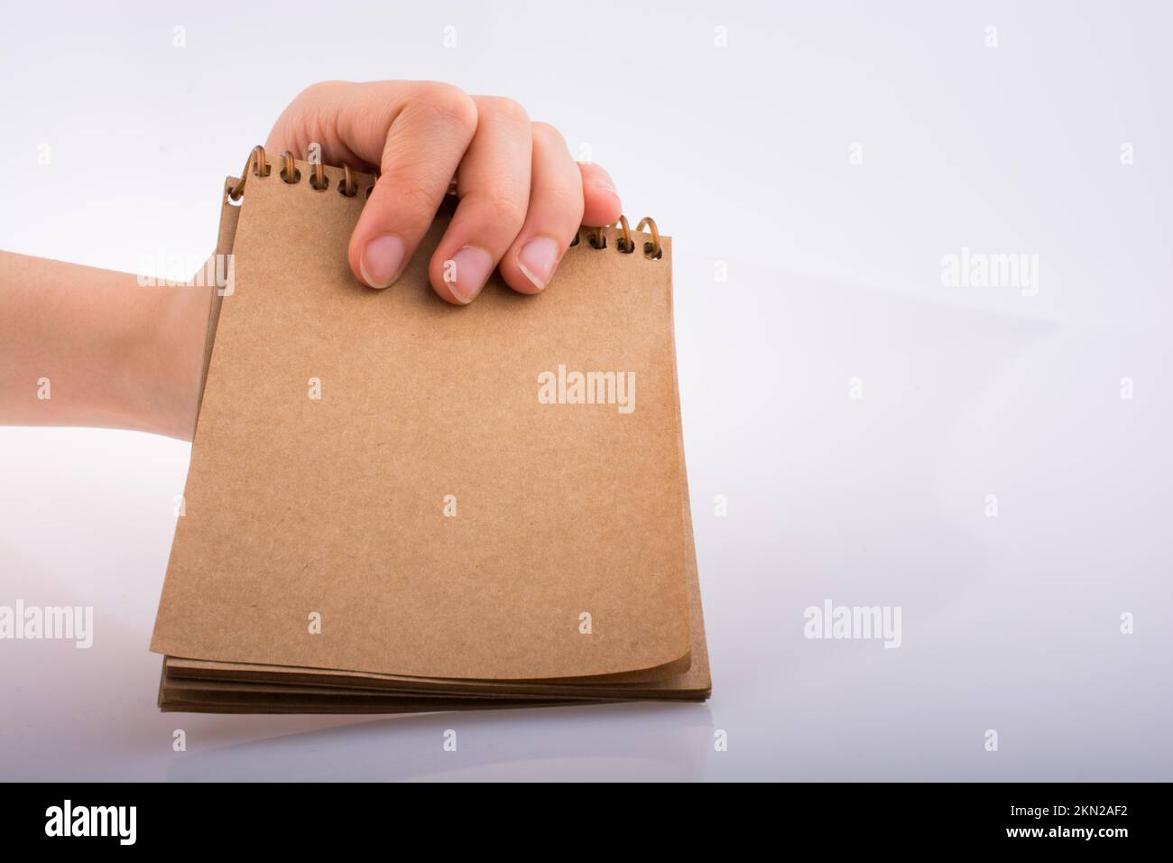 Hand holding a brown spiral notebook on a white background Stock Photo ...
