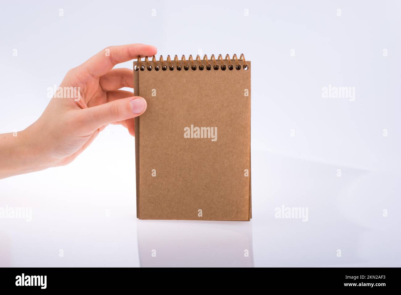 Hand holding a brown spiral notebook on a white background Stock Photo ...