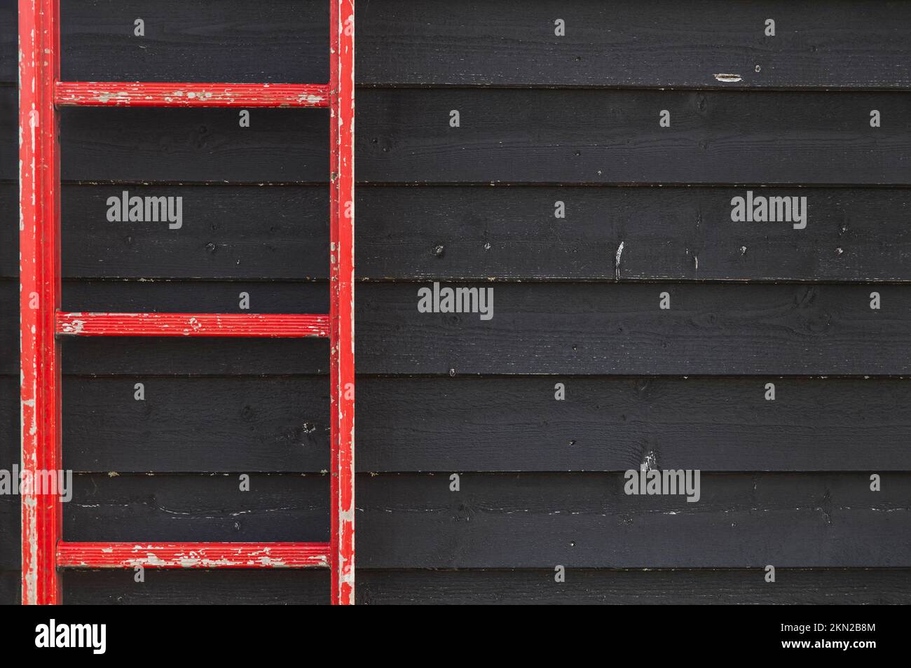 Red ladder near black wooden wall. Background Stock Photo - Alamy