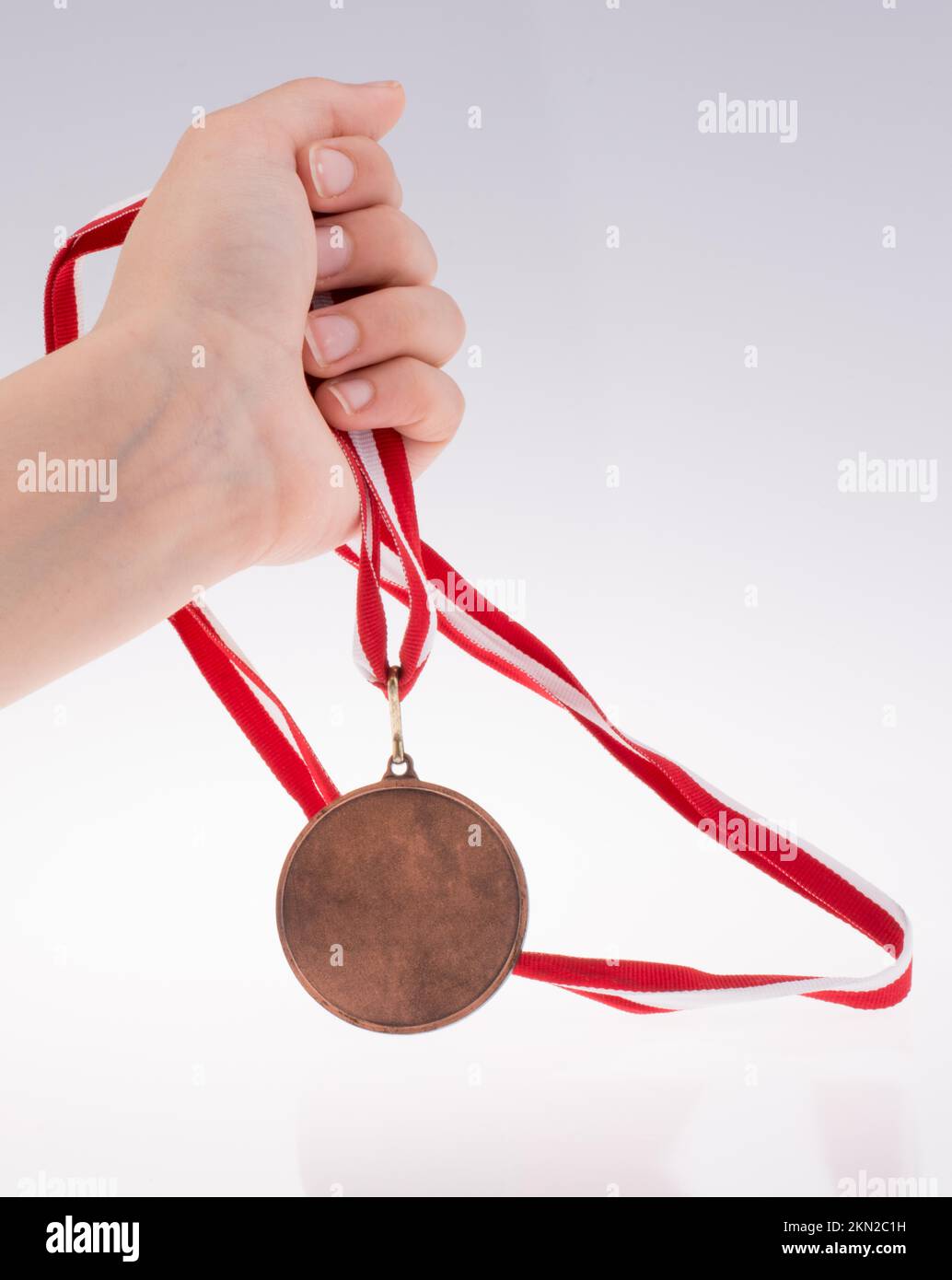 Hand holding a medal with red and white ribbon Stock Photo - Alamy