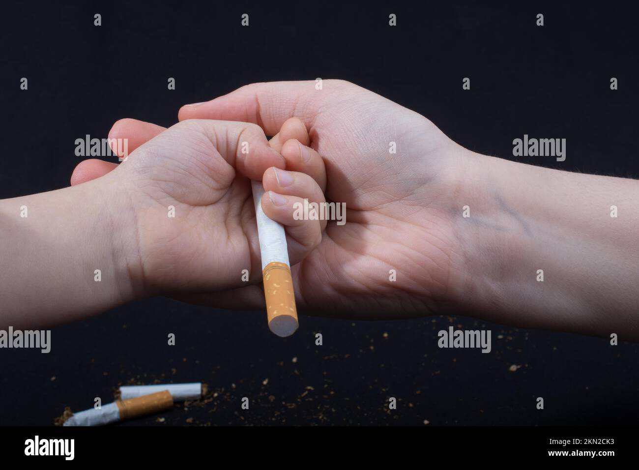 Hand is giving out cigarette on a black background Stock Photo - Alamy