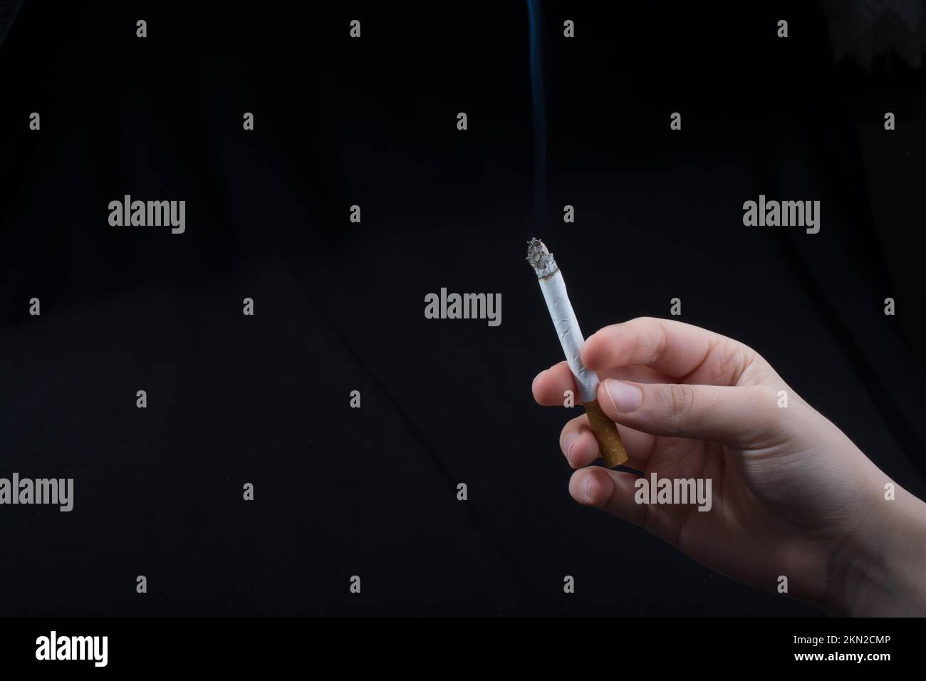 Hand is holding smoking cigarette with smoke around Stock Photo - Alamy