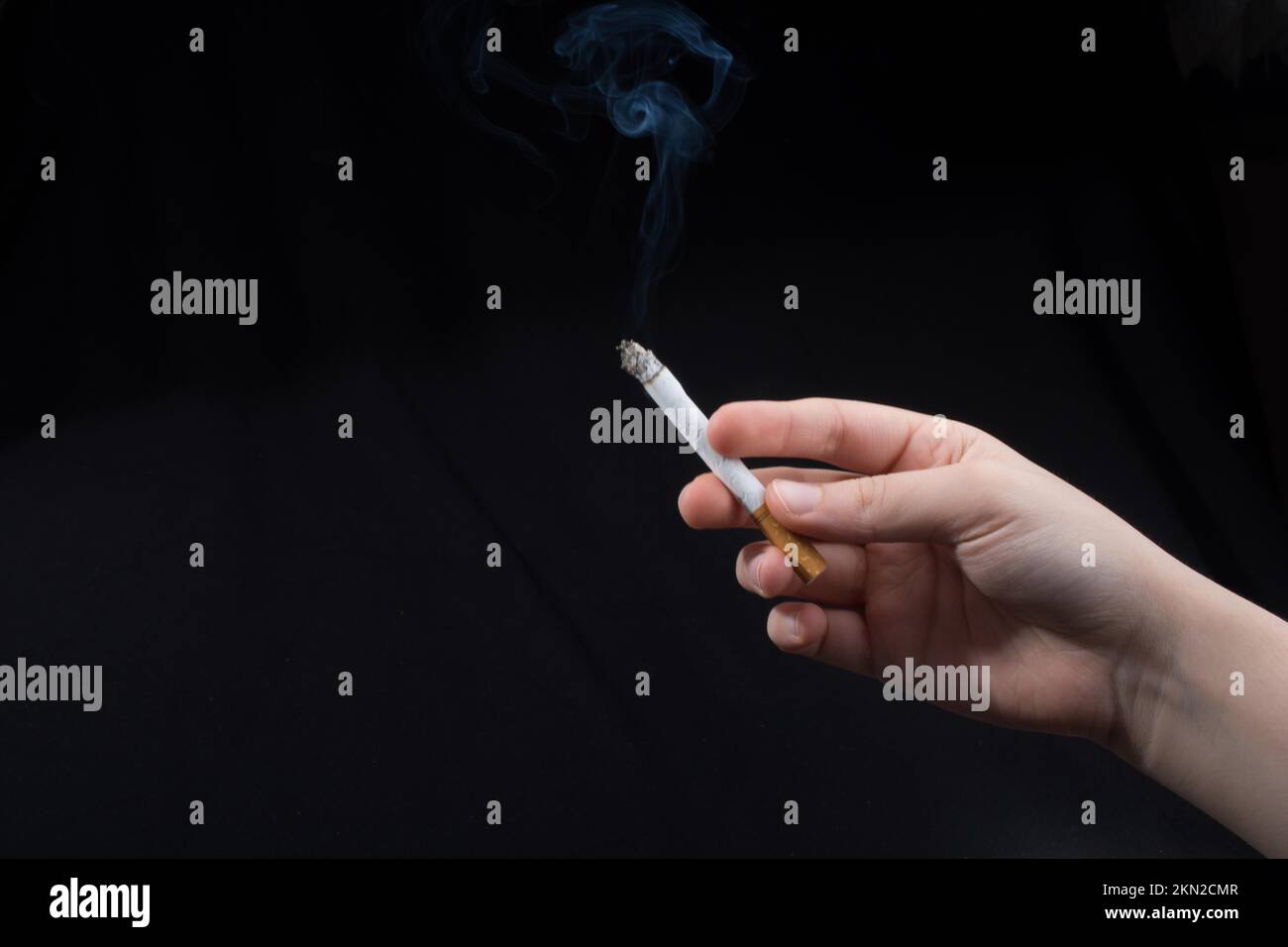 Hand is holding smoking cigarette with smoke around Stock Photo - Alamy