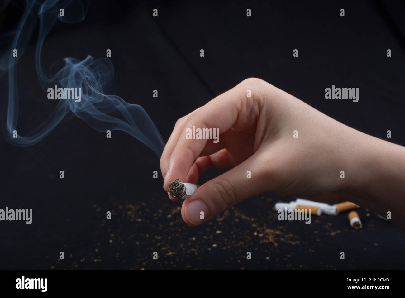 Hand is holding smoking cigarette with smoke around Stock Photo - Alamy