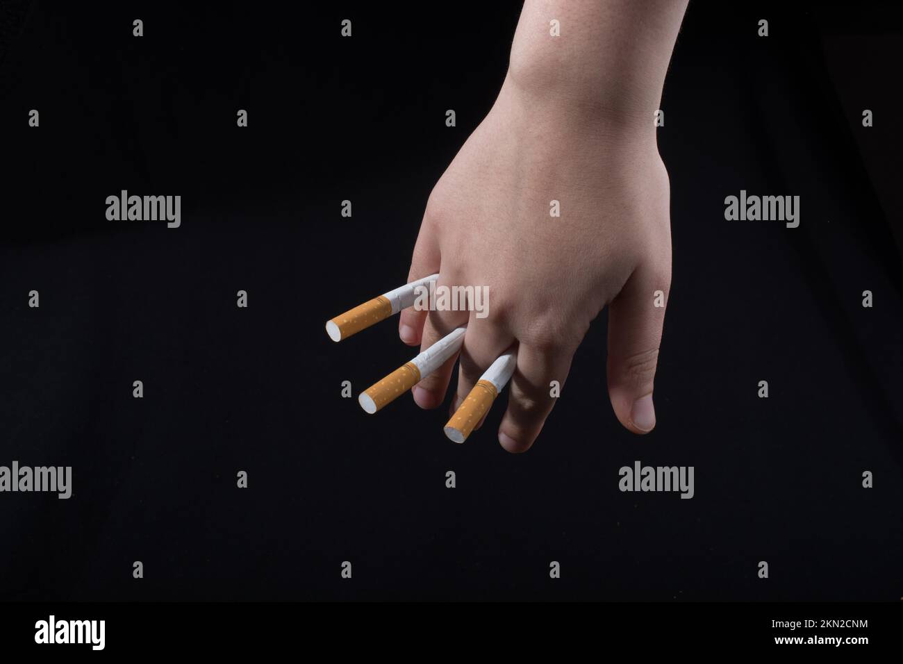 Hand is holding cigarettes between fingers on black background Stock ...