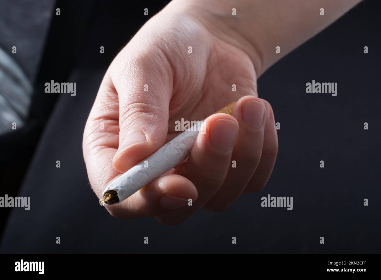 Hand is giving out cigarette on a black background Stock Photo - Alamy