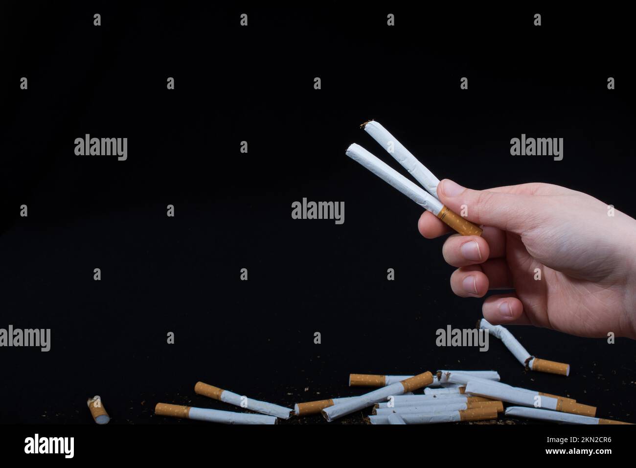 Hand is holding cigarettes on a black background Stock Photo - Alamy