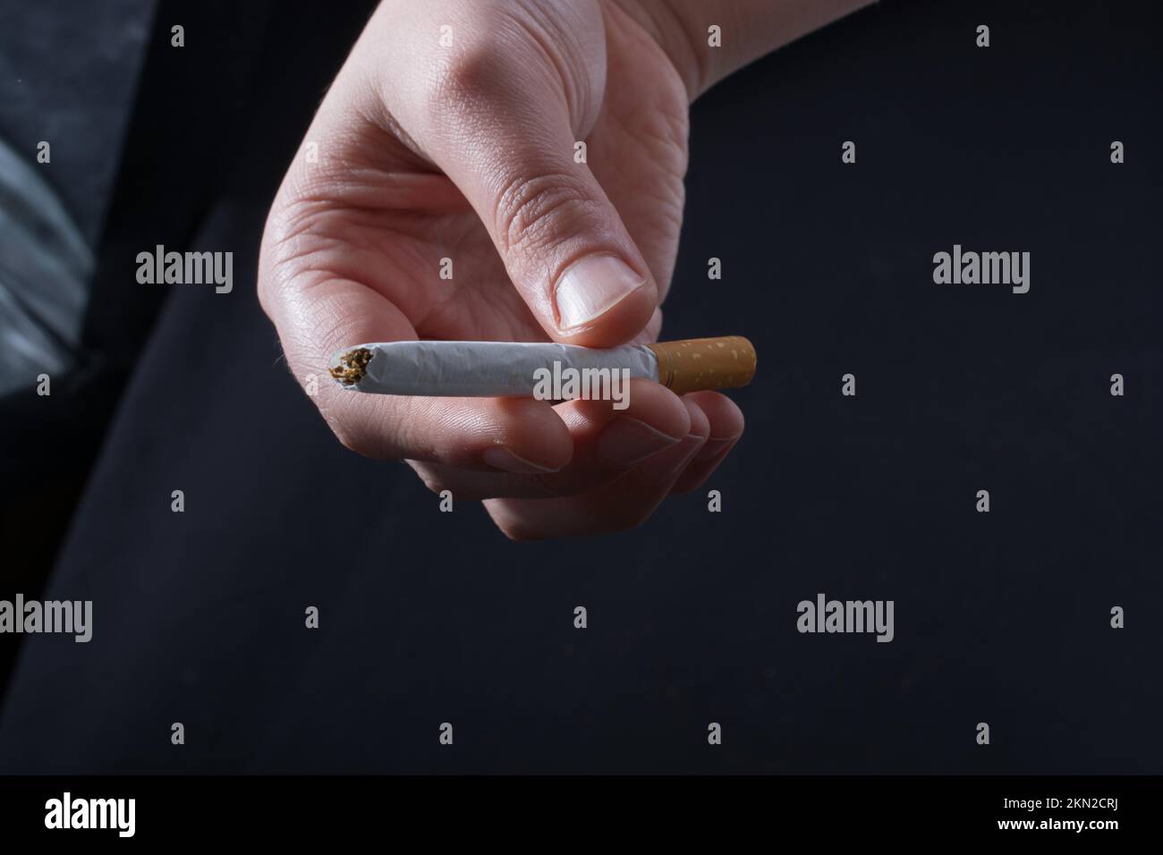 Hand is giving out cigarette on a black background Stock Photo - Alamy