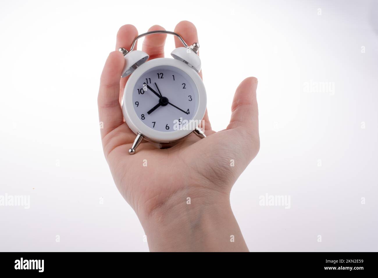 Alarm clock in hand on a white background Stock Photo - Alamy
