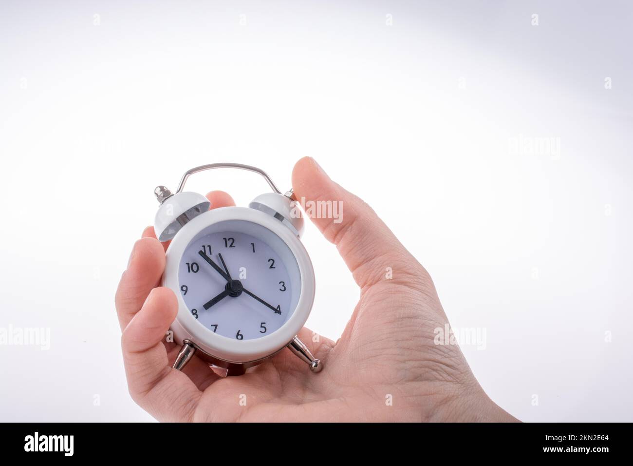 Alarm clock in hand on a white background Stock Photo - Alamy