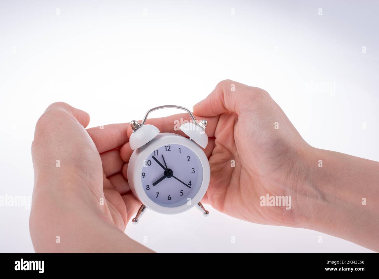 Alarm clock in hand on a white background Stock Photo - Alamy