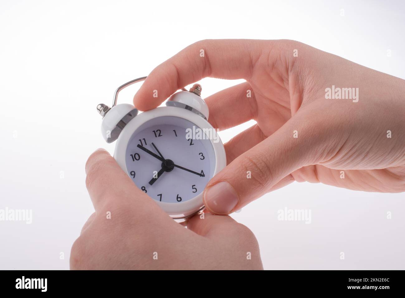 Alarm clock in hand on a white background Stock Photo - Alamy