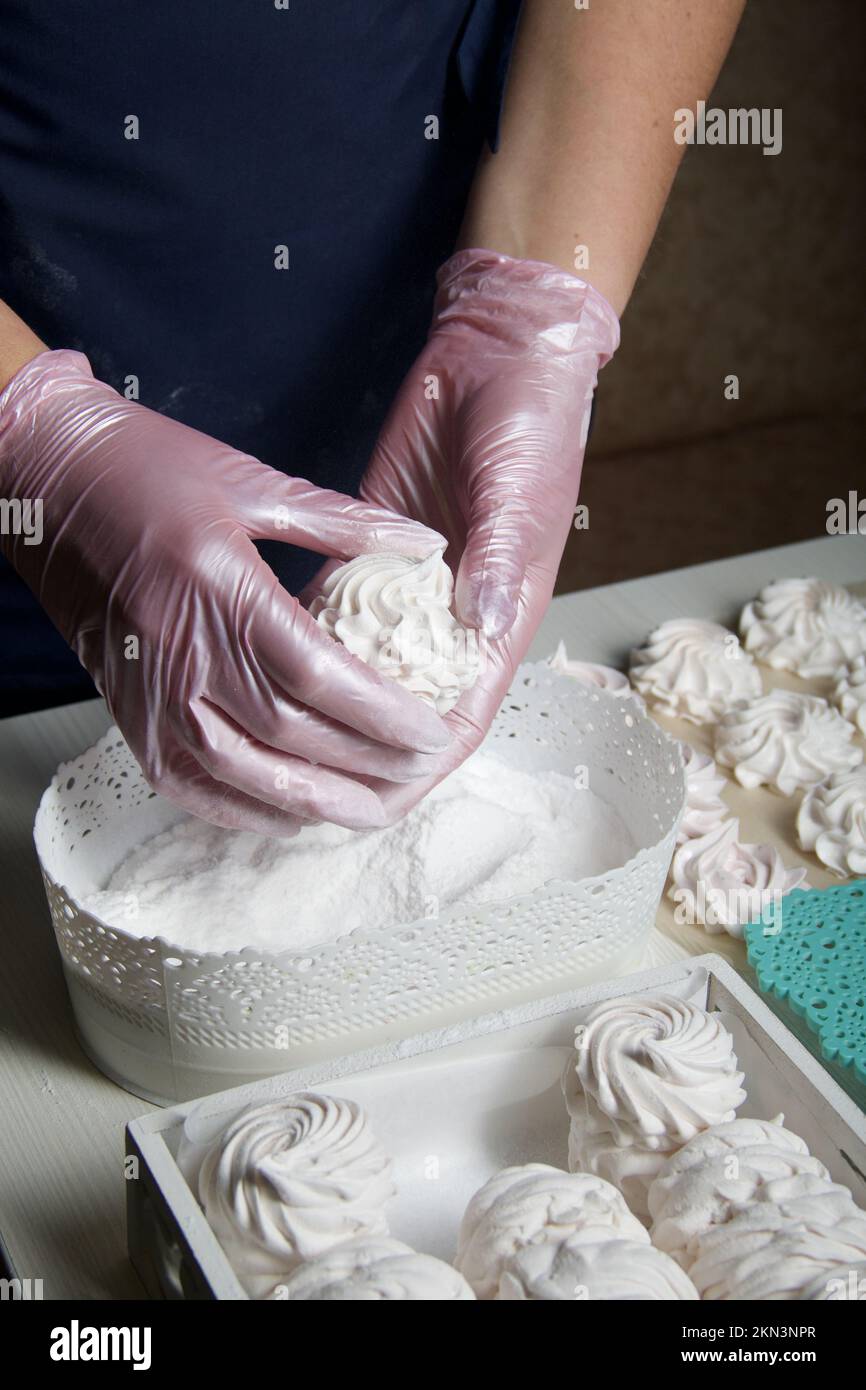 Homemade zephyr. White tray with marshmallows. A woman sprinkles ...