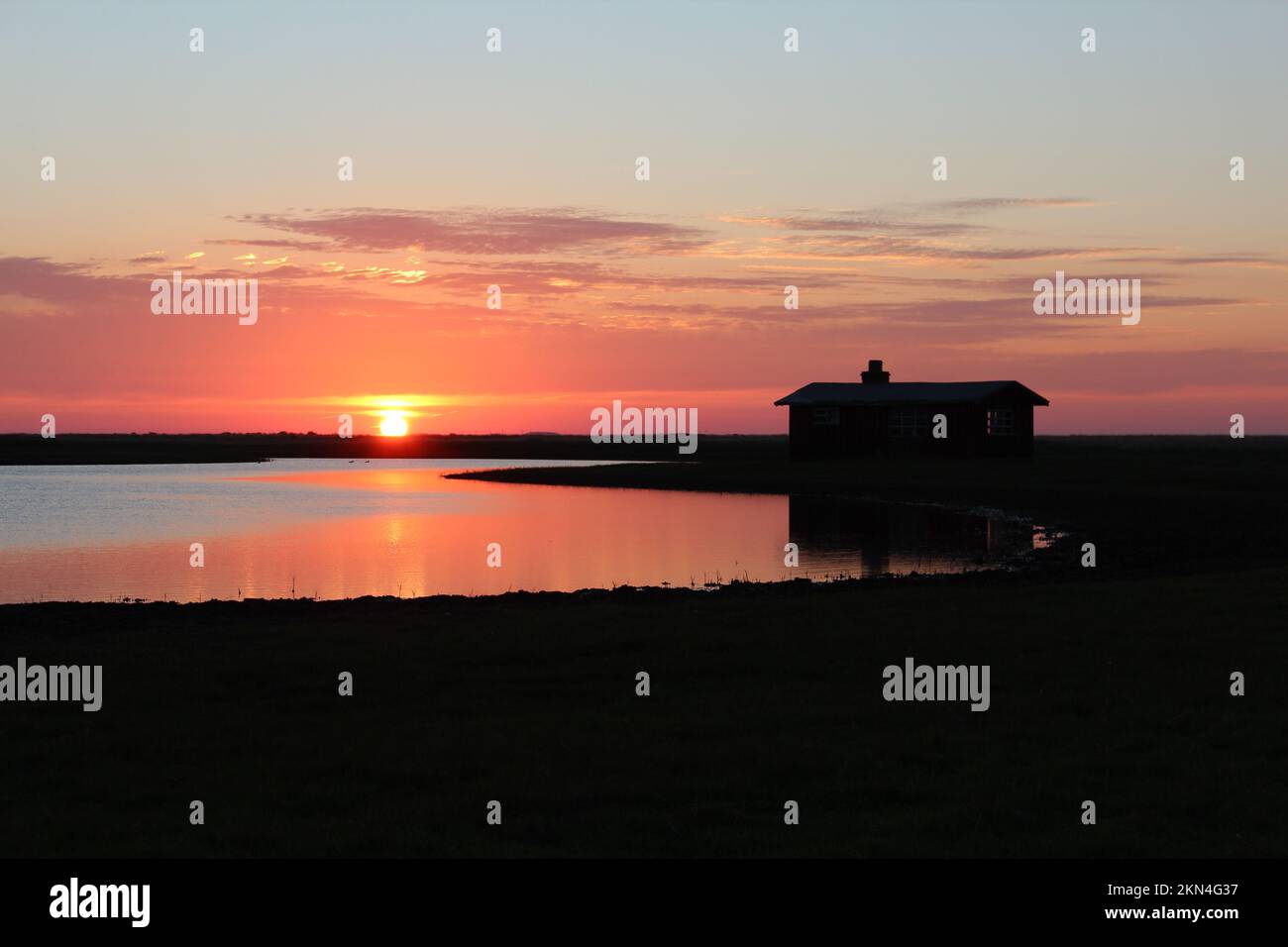 A silhouette of a hut by the lake on the sunset Stock Photo - Alamy