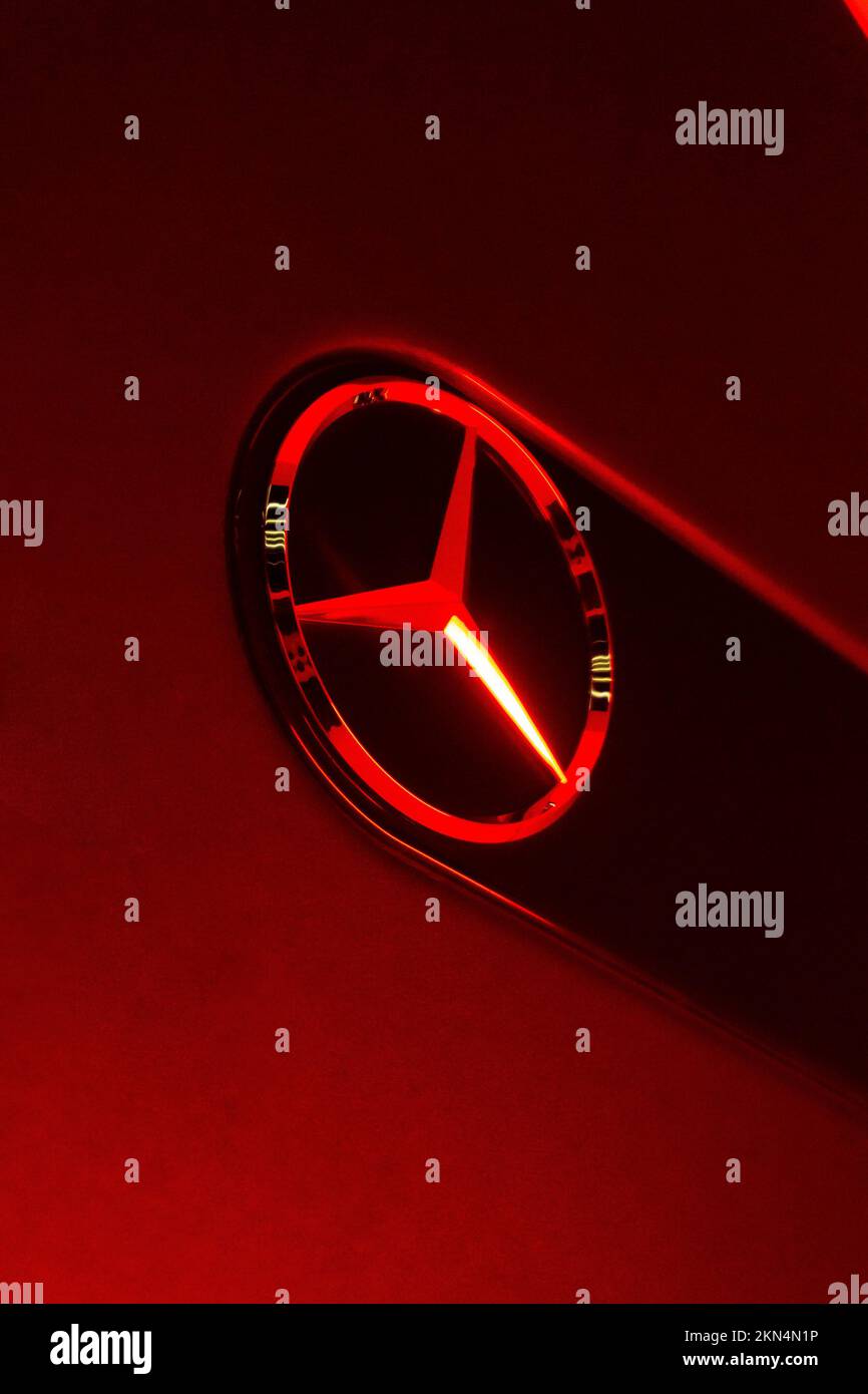 A vertical closeup of a Mercedes Benz logo reflecting red light Stock ...