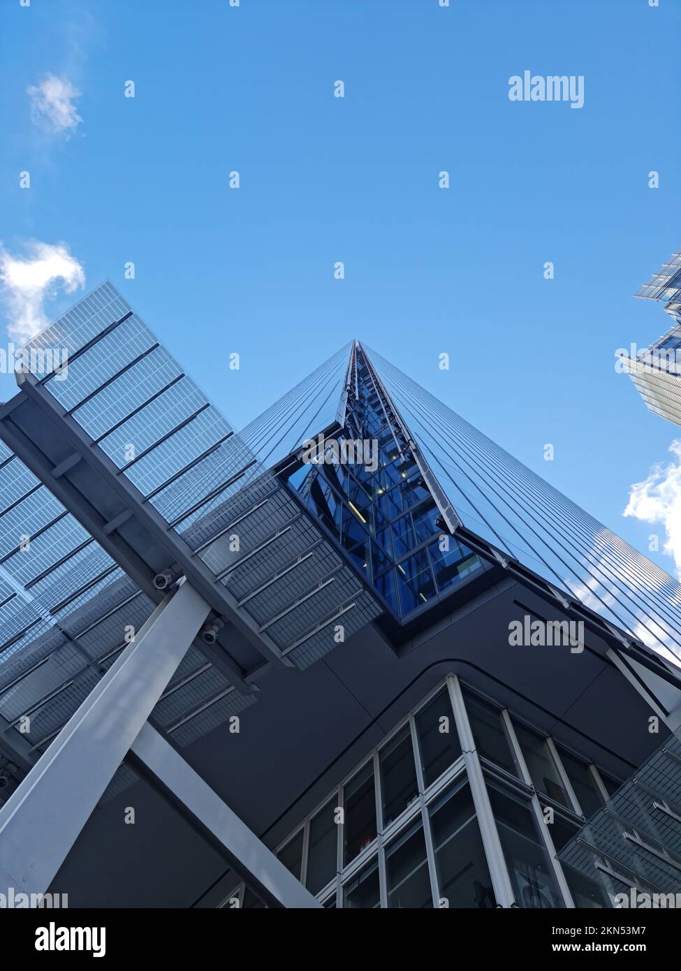 An exterior view of a tall glass building in an urban area in blue sky ...