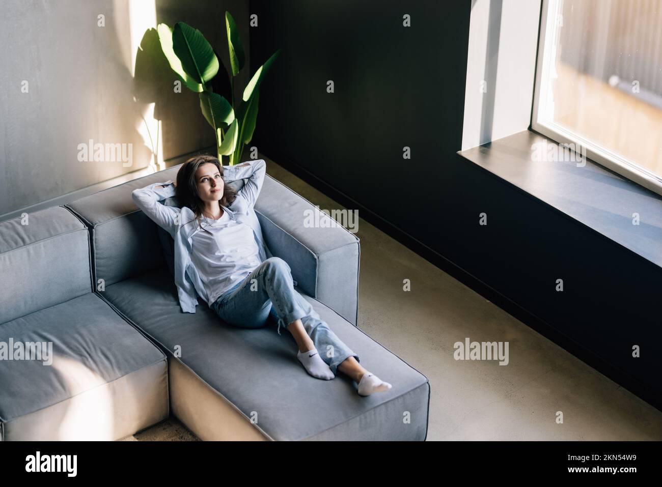Happy relaxed pretty young woman lying on sofa at home, daydreaming ...