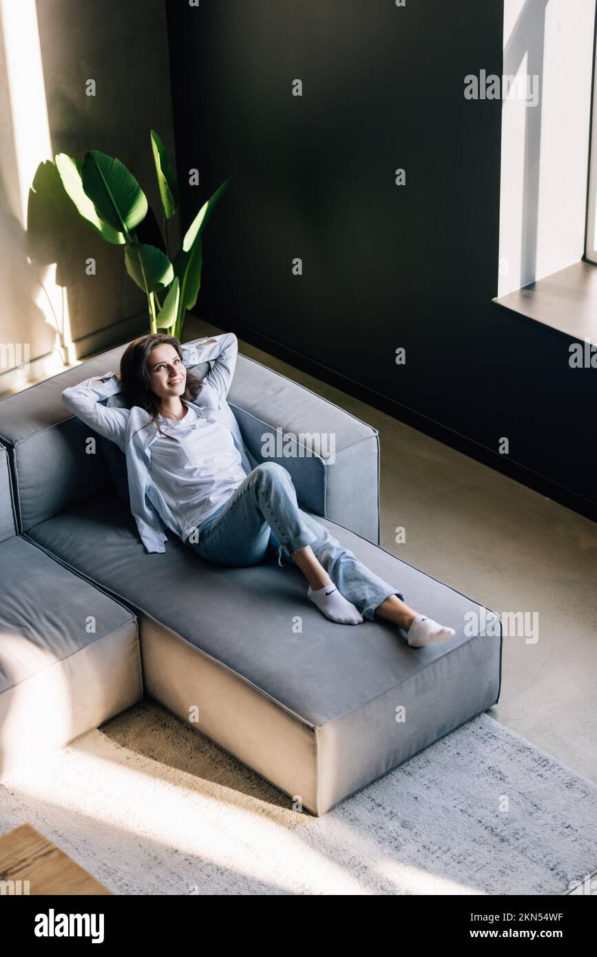 Happy peaceful young woman relaxing on comfortable couch at home with ...