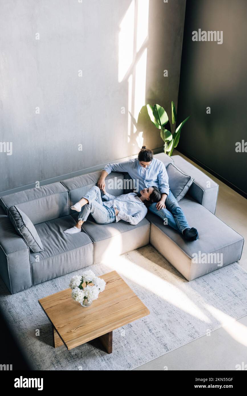 Loving couple holding hands, relaxing on cozy sofa in modern living ...
