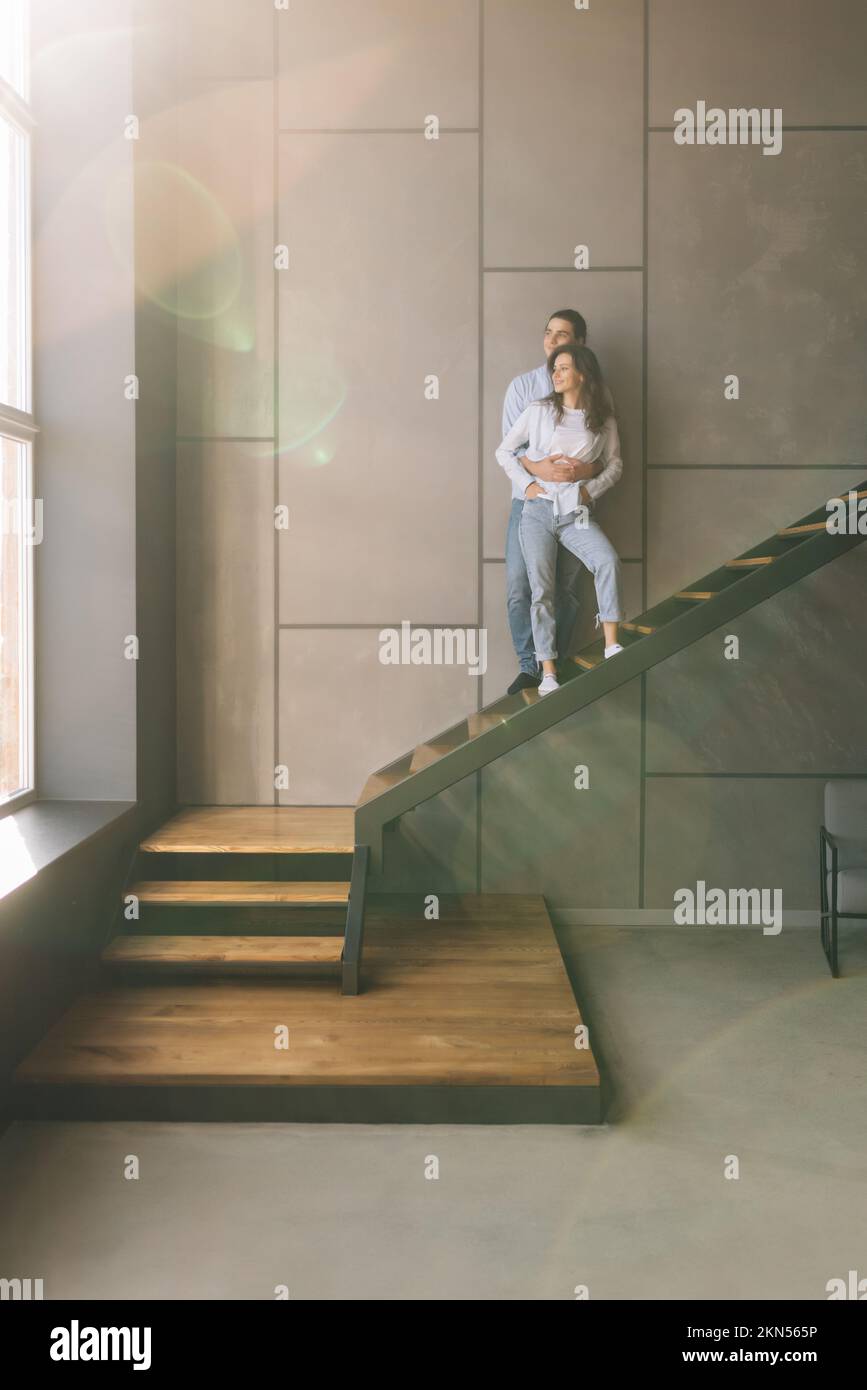 Full body photo of handsome guy and his pretty lady sitting on stairs ...