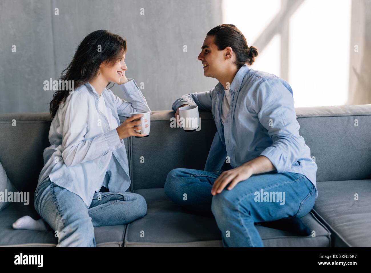 Happy young couple relaxing on couch at home with coffee. Young man and ...