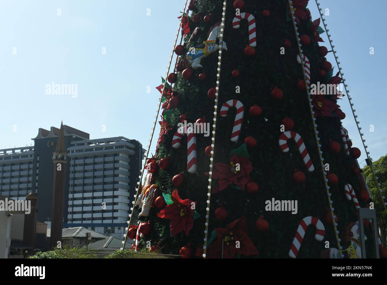 A Christmas tree out at a shopping mall near by a recognizable building ...