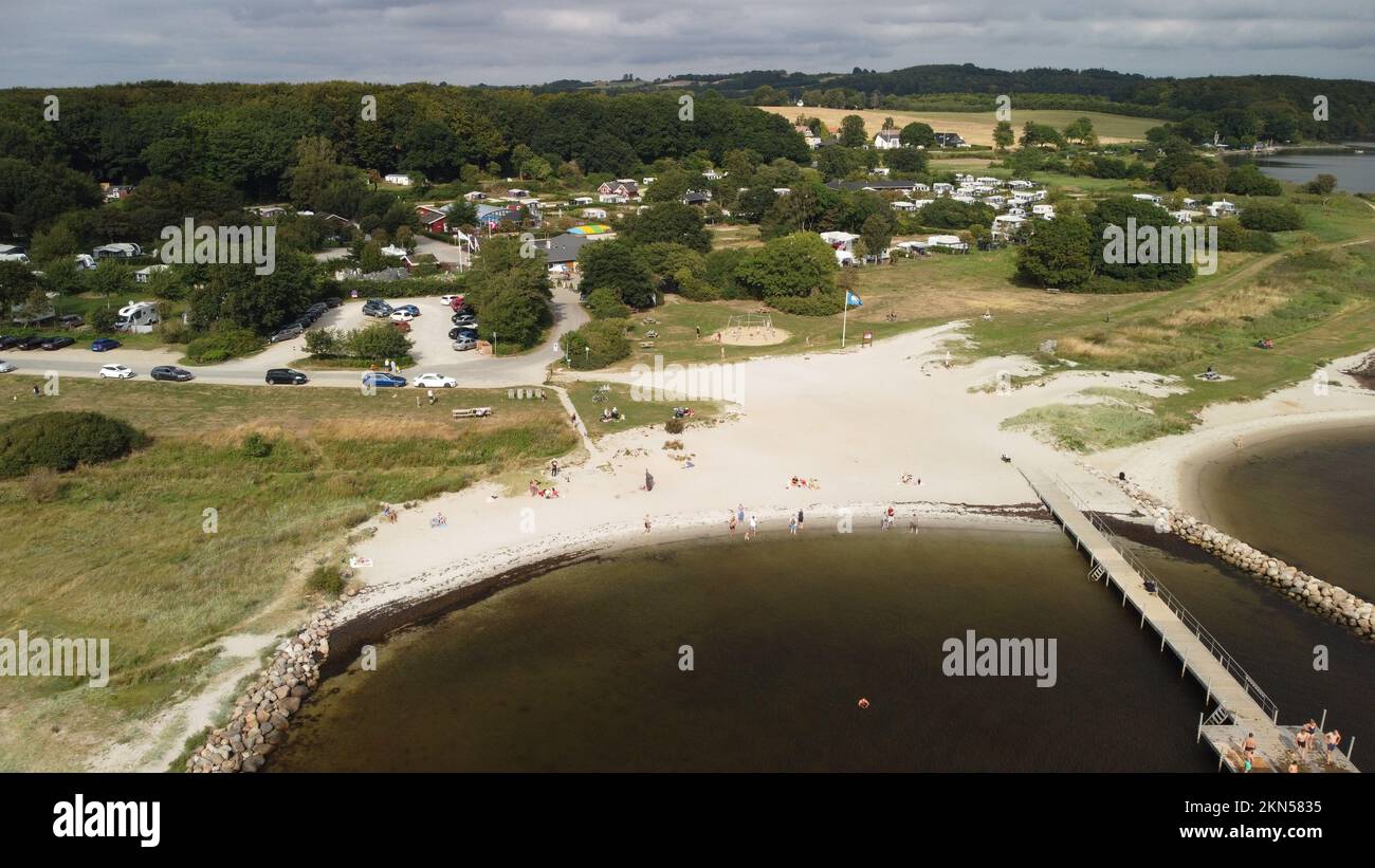 An Aerial view of green wood trees beach with a pier with blue sky on ...