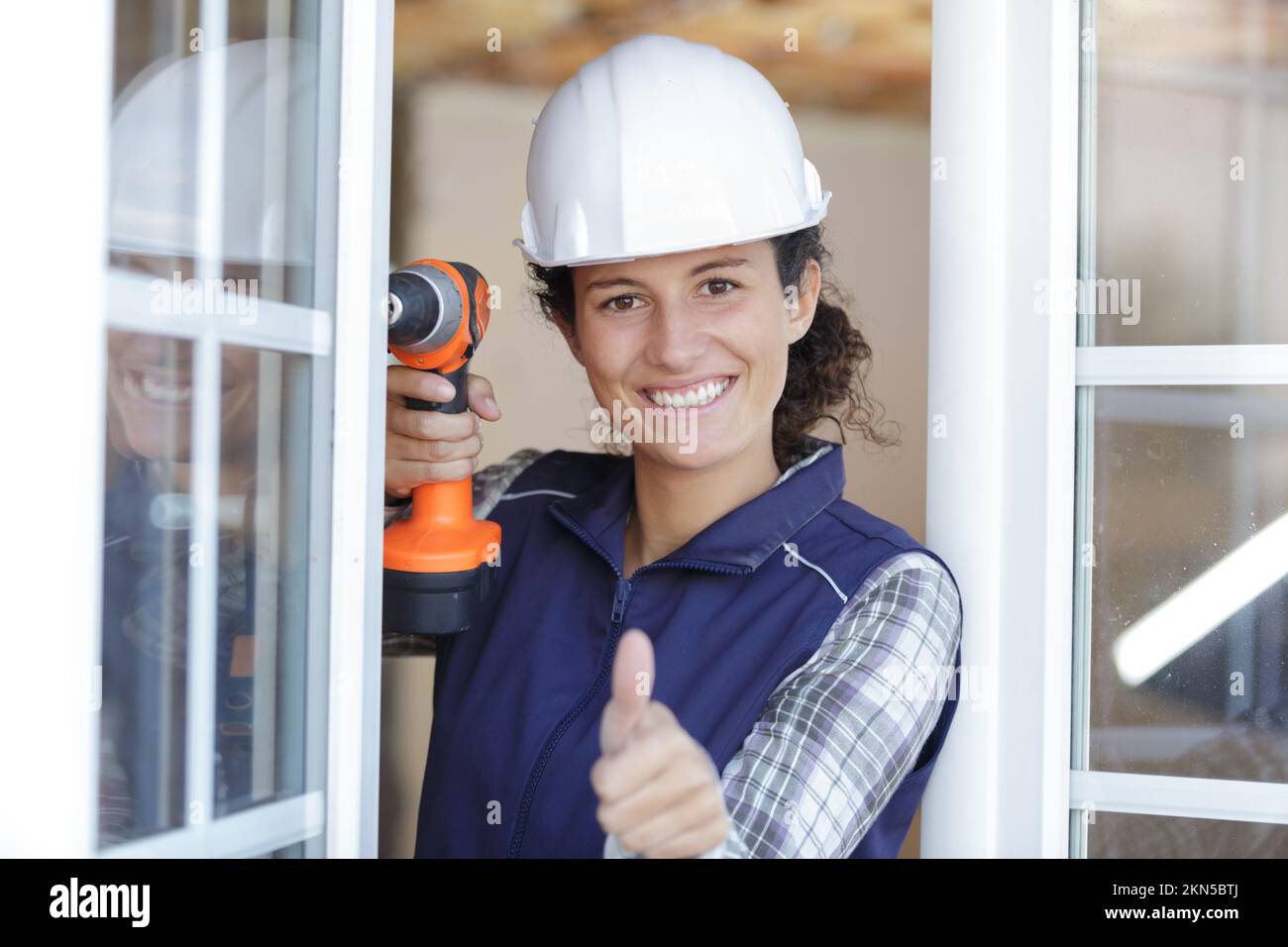 female builder installing a window Stock Photo - Alamy