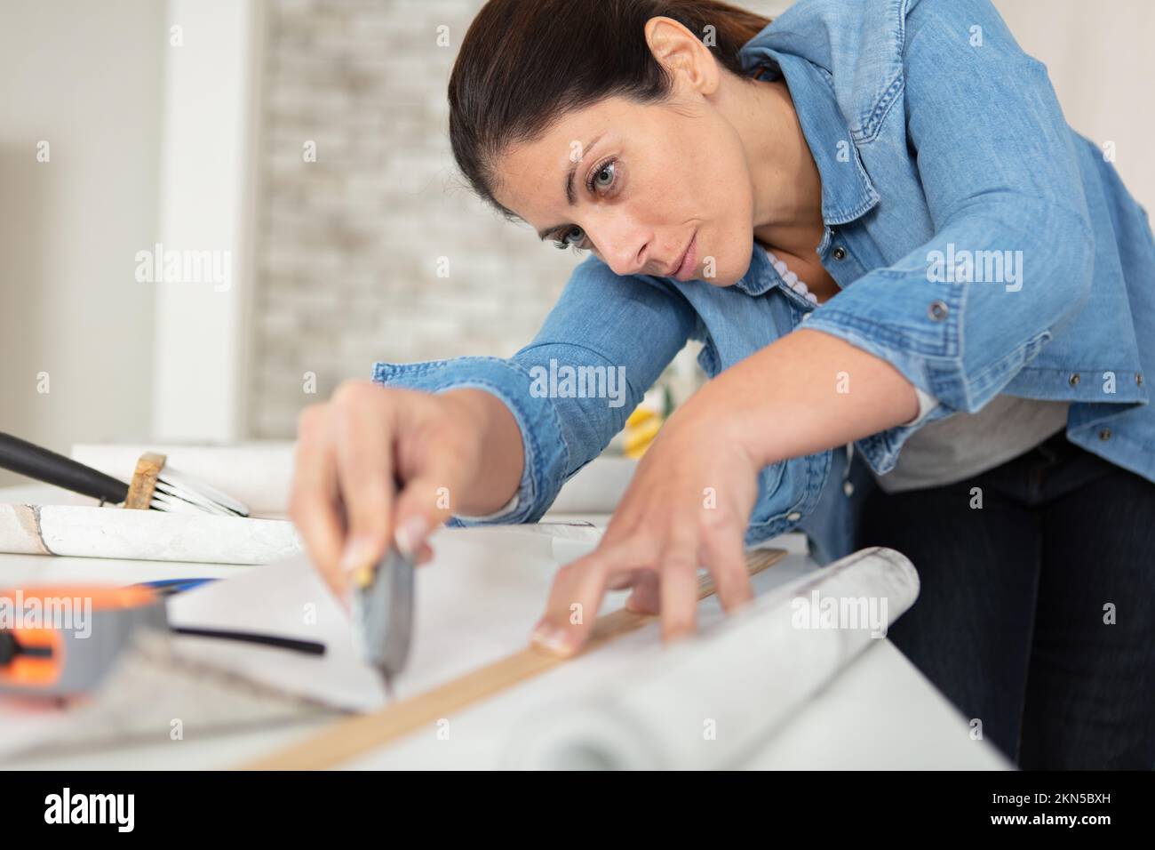 woman cutting wallpaper with a ruler and a cutting blade Stock Photo ...