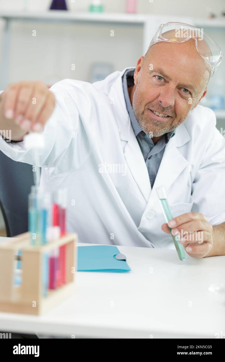 happy mature lab man pouring fluids in pipettes Stock Photo - Alamy
